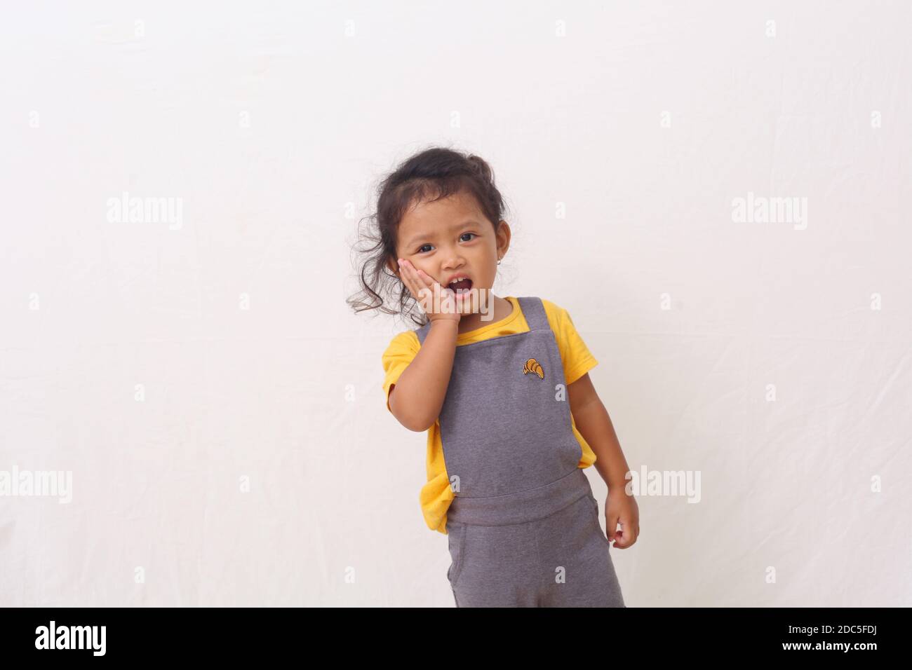 Adorable asian girl standing while showing a cute expression. Isolated ...