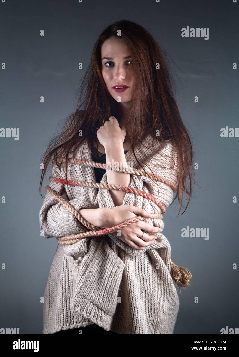 Photo of young binded woman with rope on sweater on grey background ...