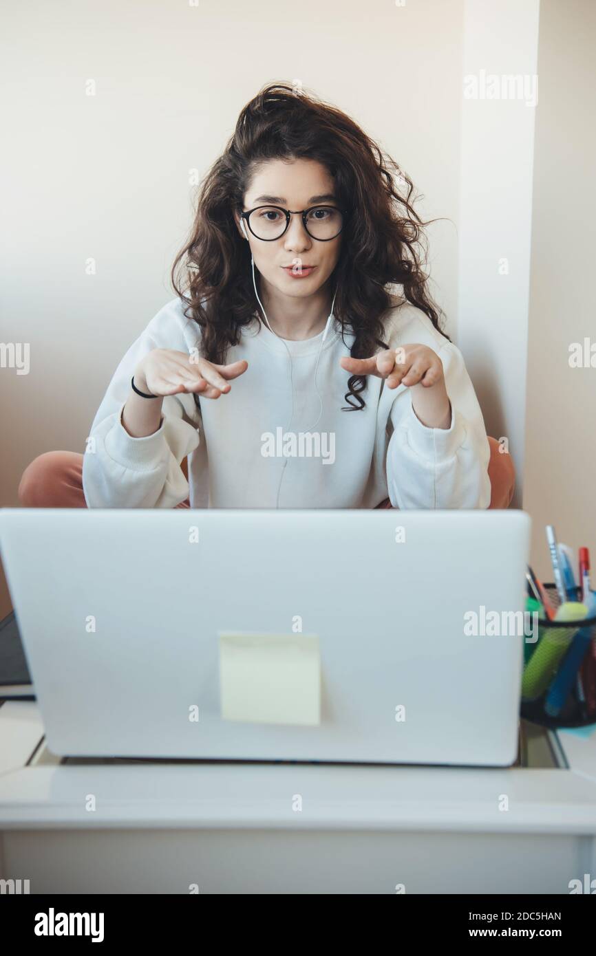 Adorable woman is explaining something at the laptop while having ...