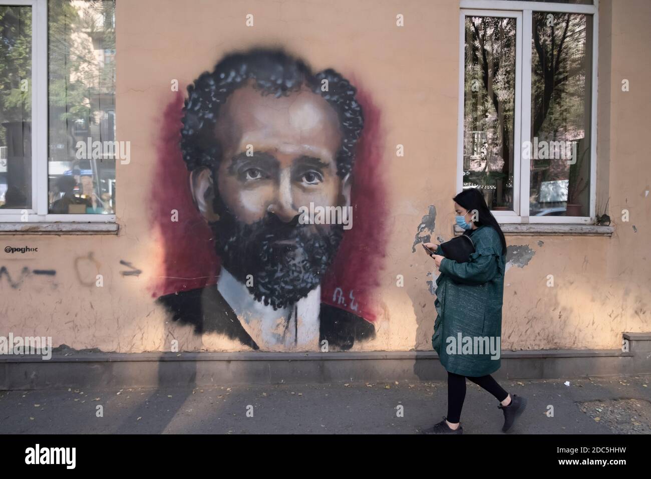 A pedestrian walks past a wall with painted image of Hovhannes Tumanyan ...
