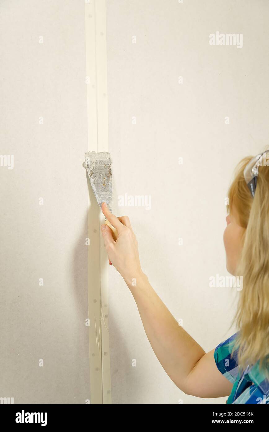 Woman putty plaster. Builder female indoor worker plastering wall with ...