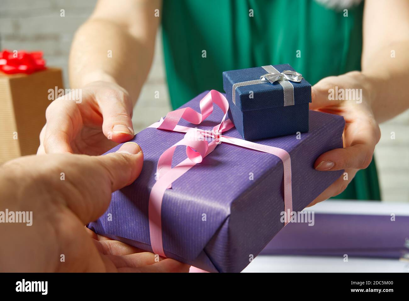 Female hands holding a small gift box wrapped in packing paper. To give ...