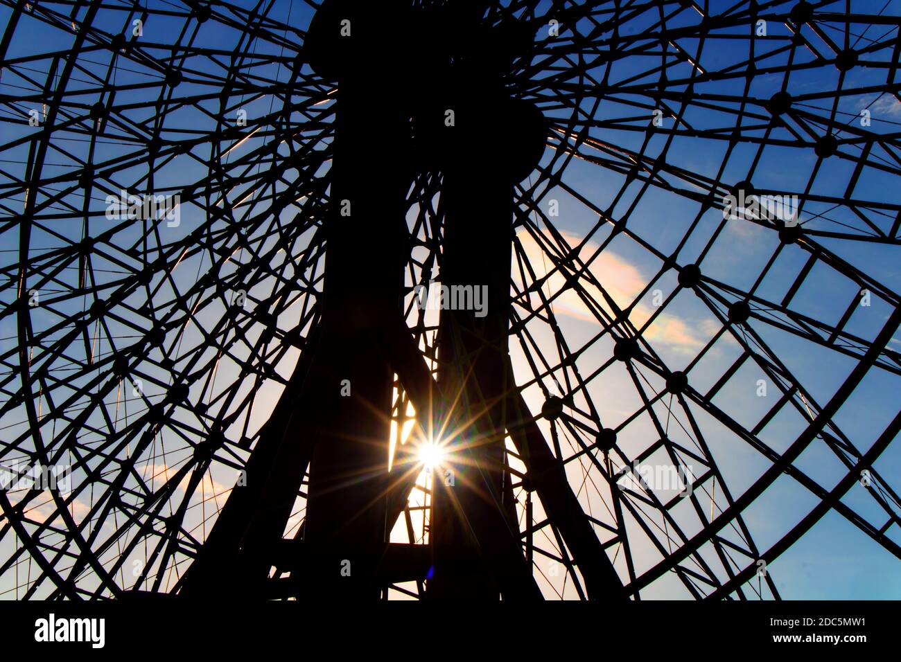 The sun's rays shine through the construction of a carousel. The ...