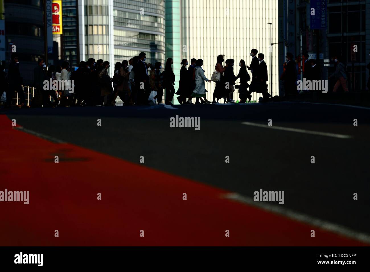 People wearing face masks walk at Shinjuku shopping district in Tokyo ...
