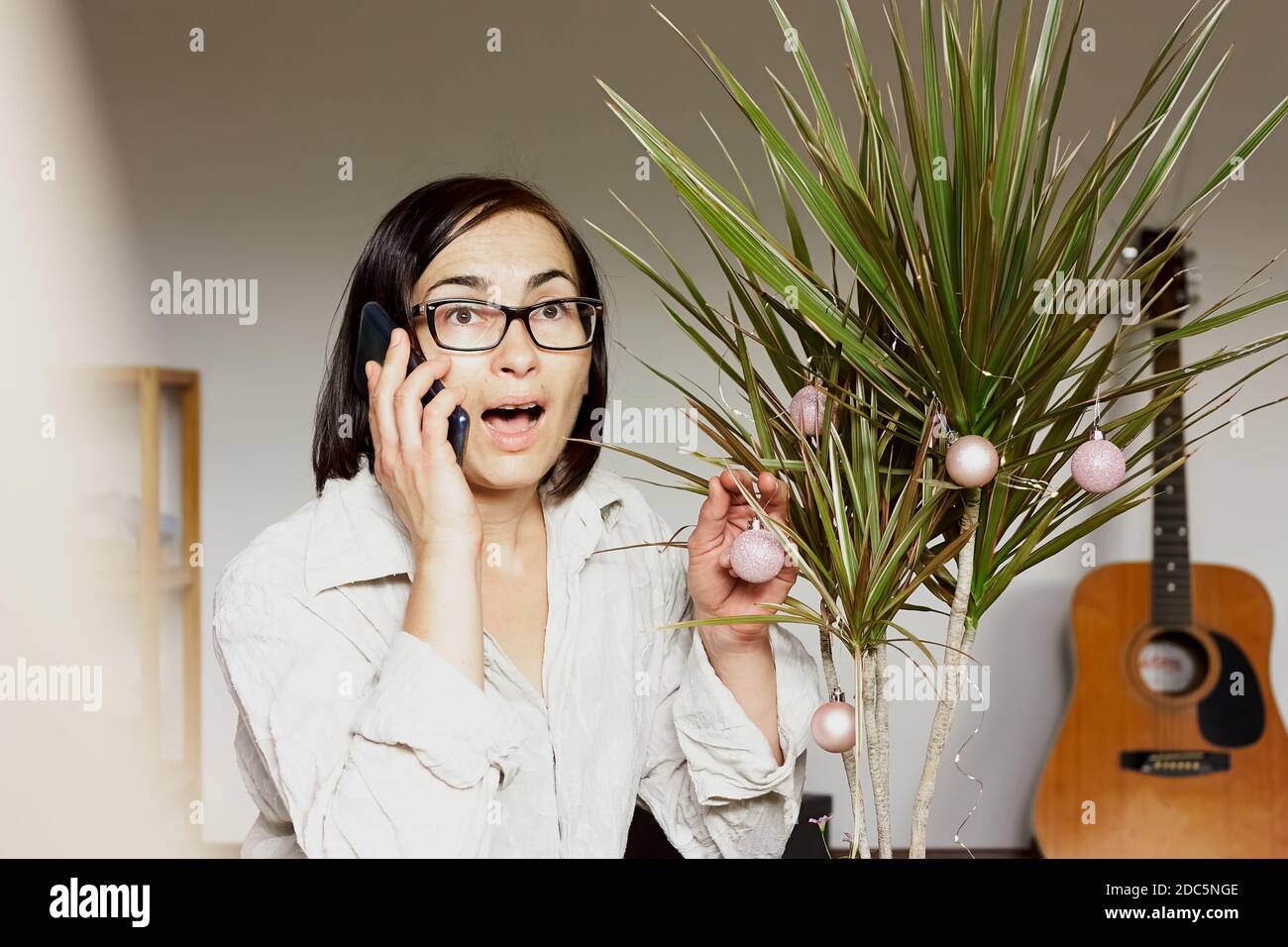 Brunette woman decorates a palm tree like a Christmas tree and receives ...