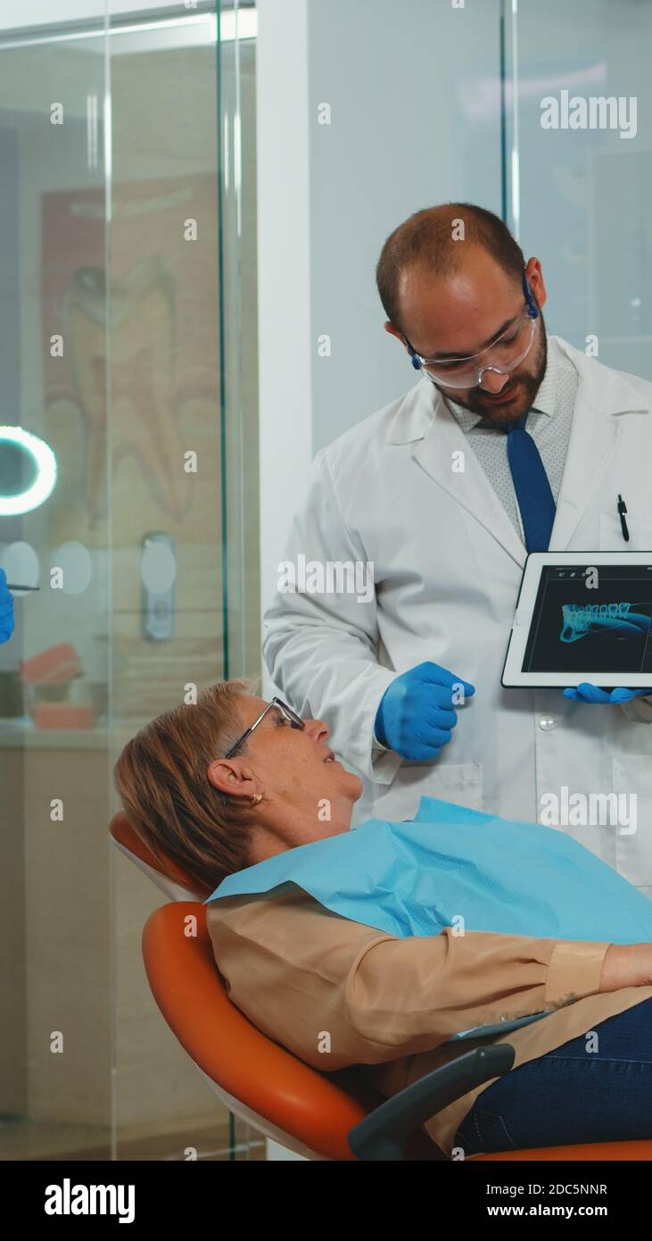 Dentistry doctor showing x-ray of teeth to patient using tablet in ...