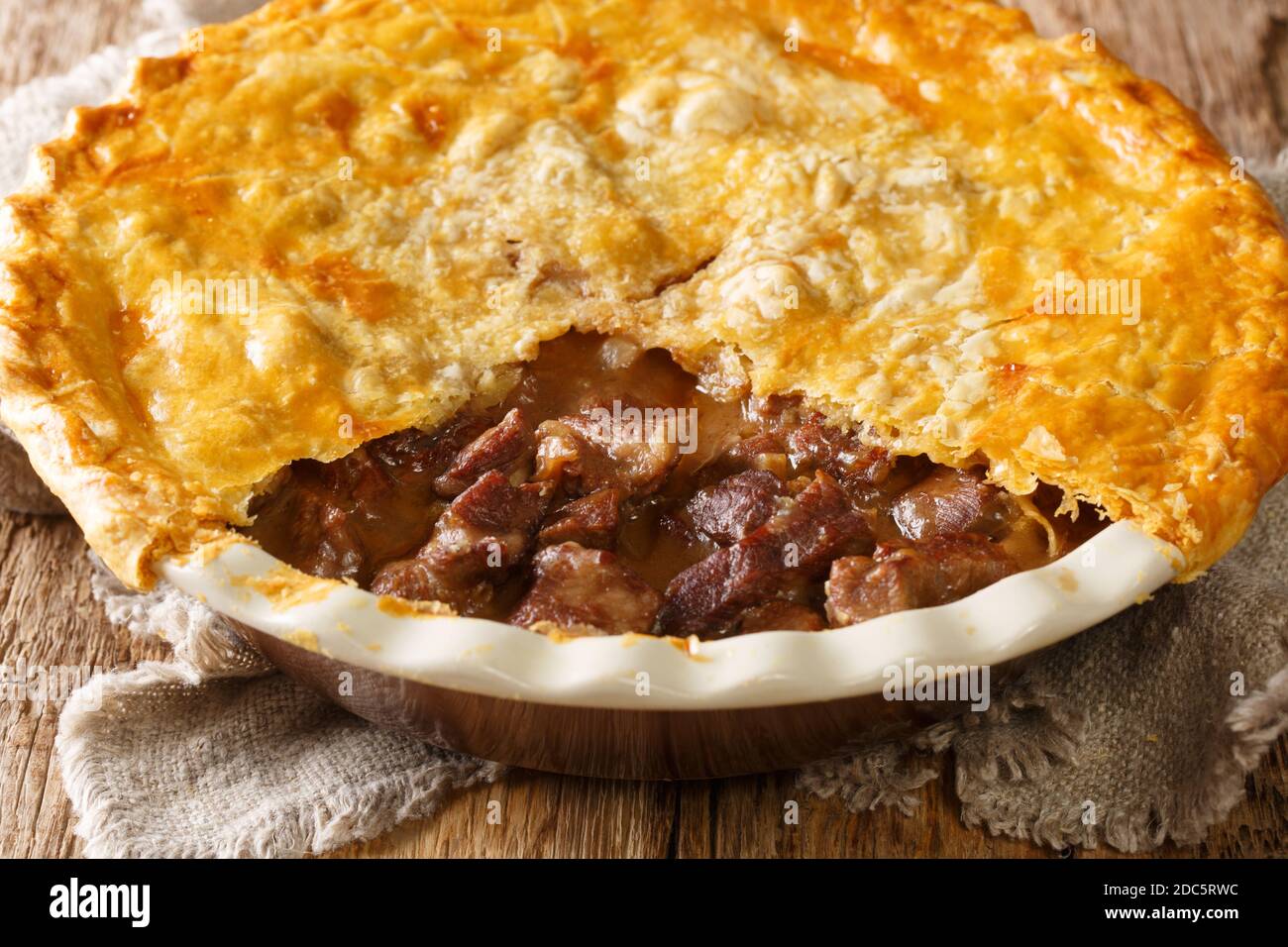 English beef steak pie with crispy puff pastry close-up in a baking ...