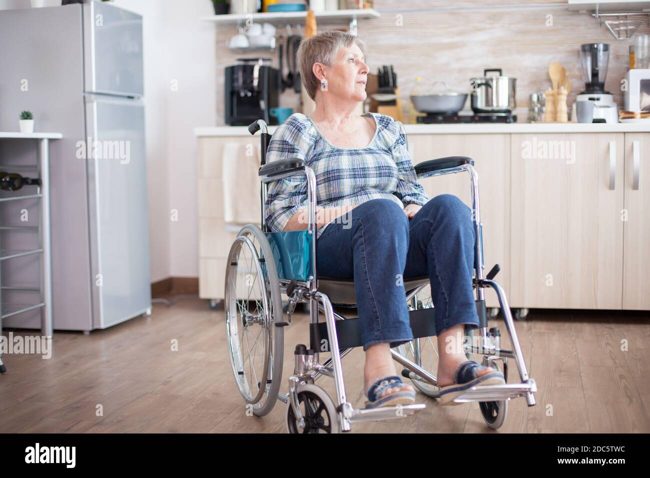 Depressed handicapped senior woman in wheelchair from leg injury ...