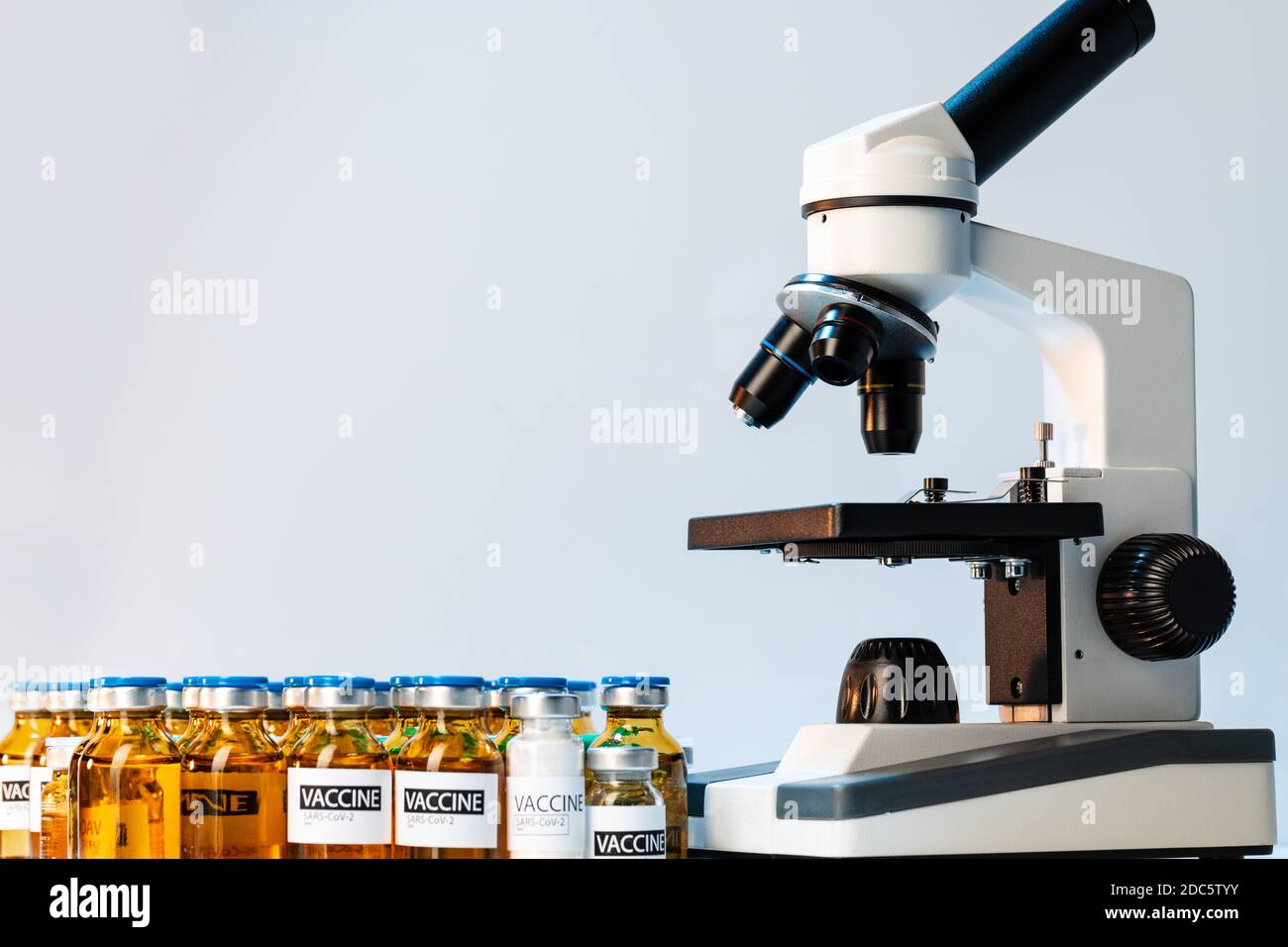 Vial of Covid-19 vaccine next to a microscope Stock Photo - Alamy