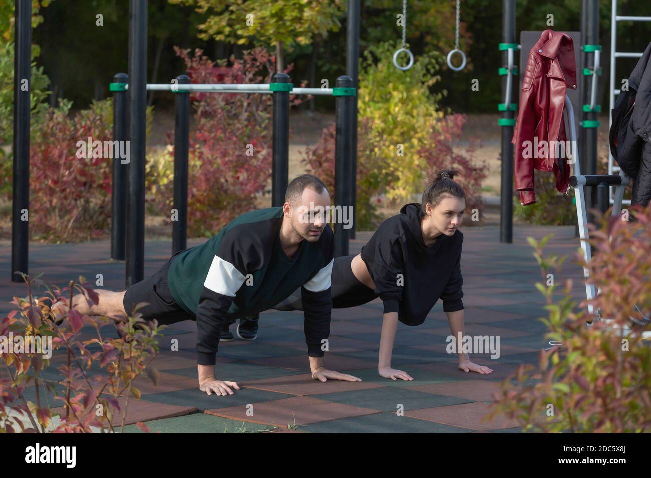 Athletic young couple doing plank exercises at park playground Stock ...
