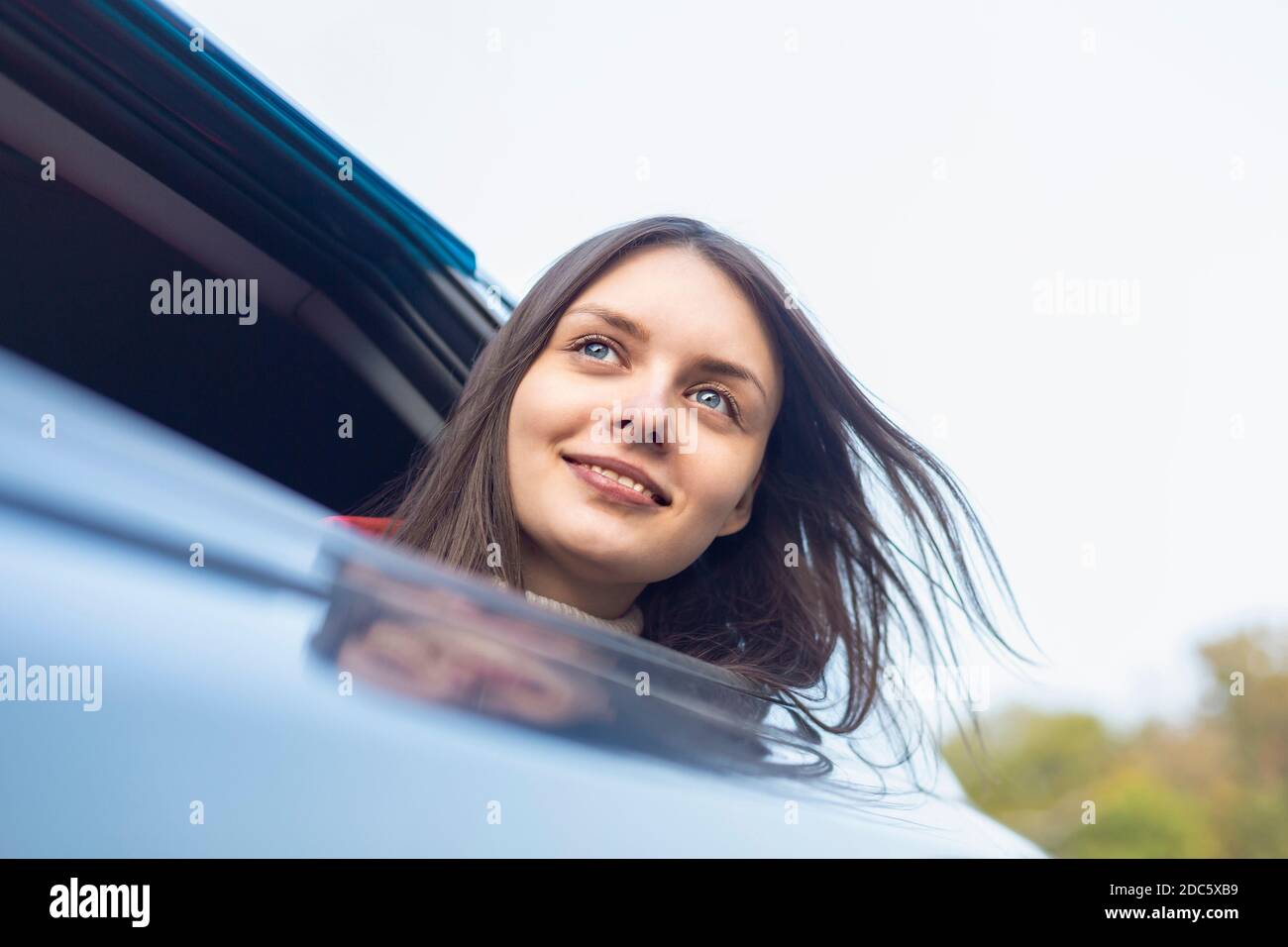 Portrait happy, carefree young woman leaning out car window Stock Photo ...