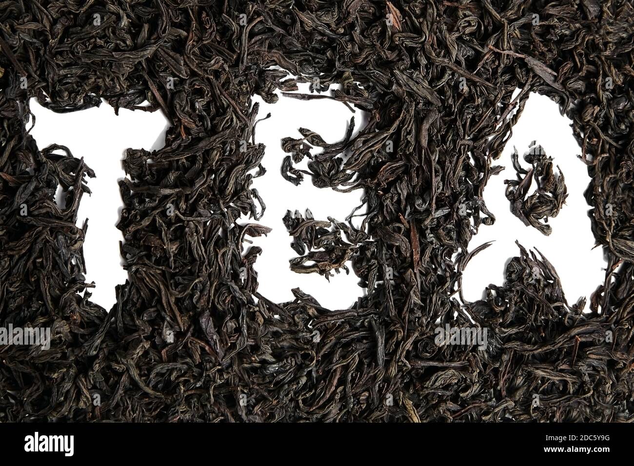Dry black tea leaves. Isolated on white background. Inscription, word ...