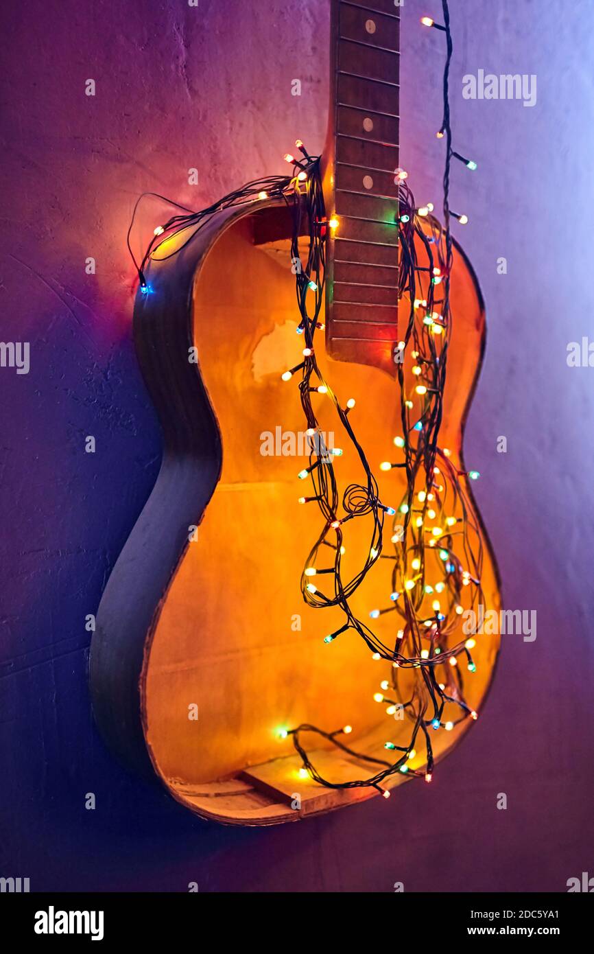 Old broken wooden guitar decorated bright glowing garland. Musical ...