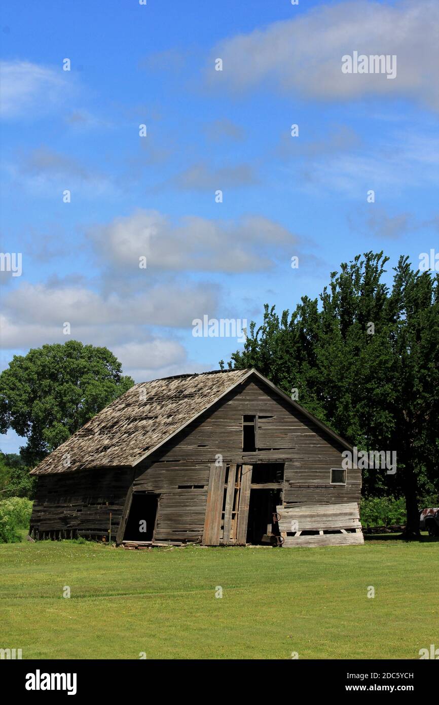 Old Kansas country Barn with green grass and blue sky with white clouds ...