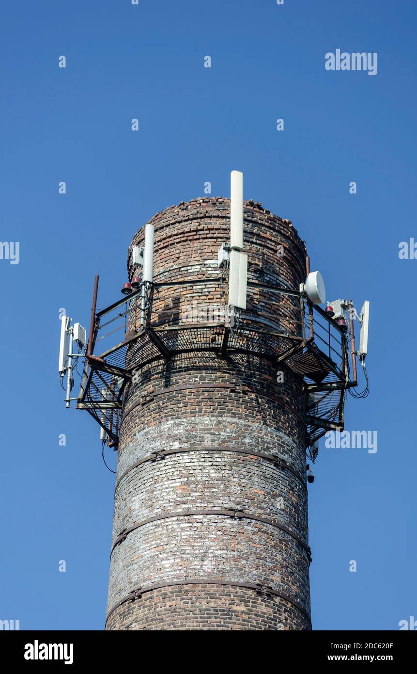 An old brick factory chimney with various antennas. A variety of modern ...