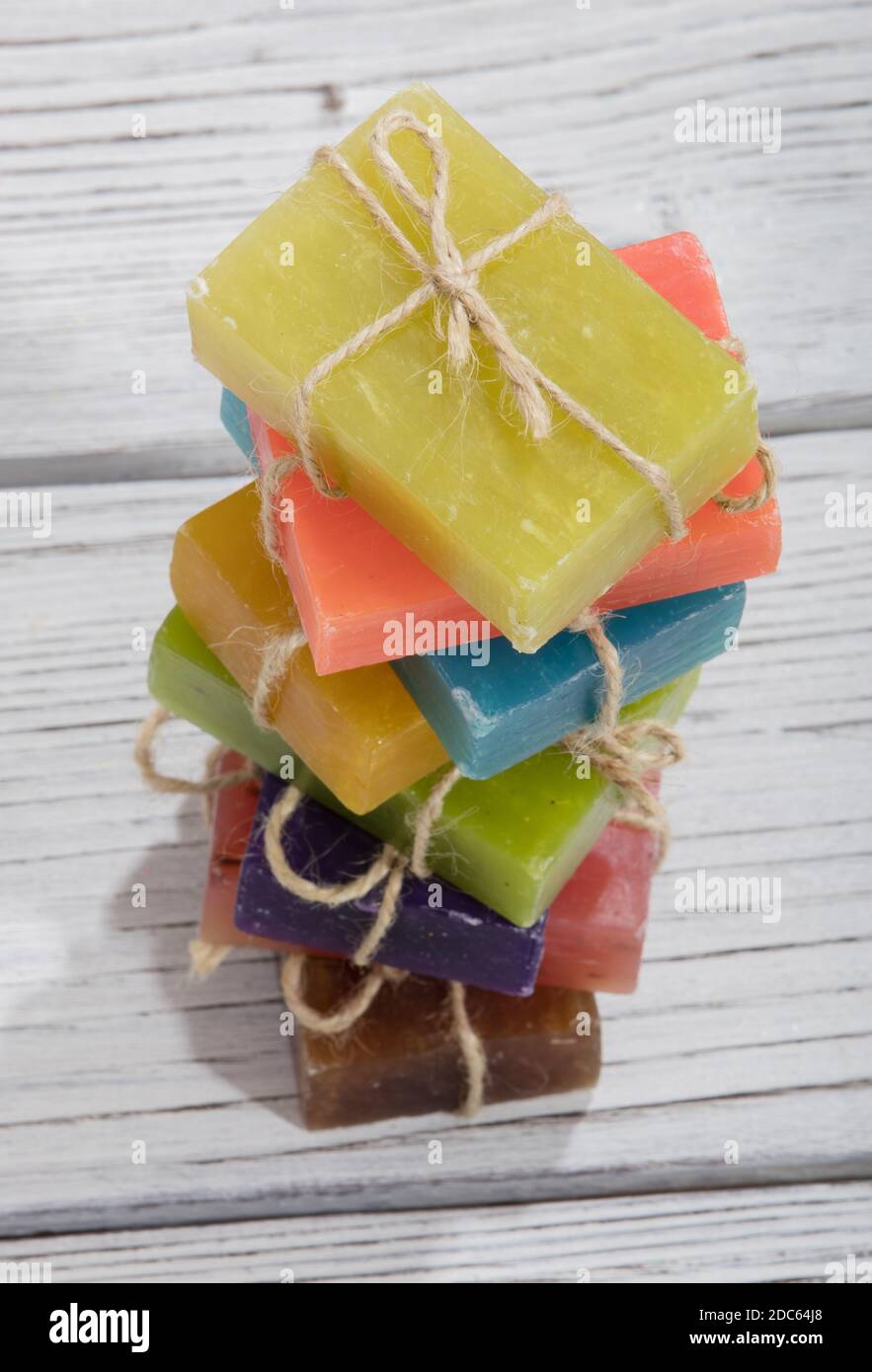 A stack of colorful scented soap bars with brown ribbon on wooden ...