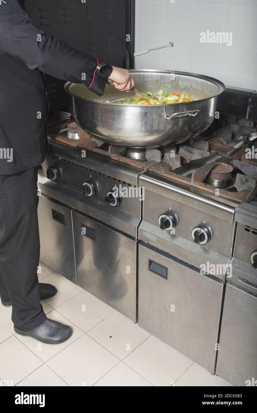 A chef cooking at a commercial kitchen Stock Photo - Alamy
