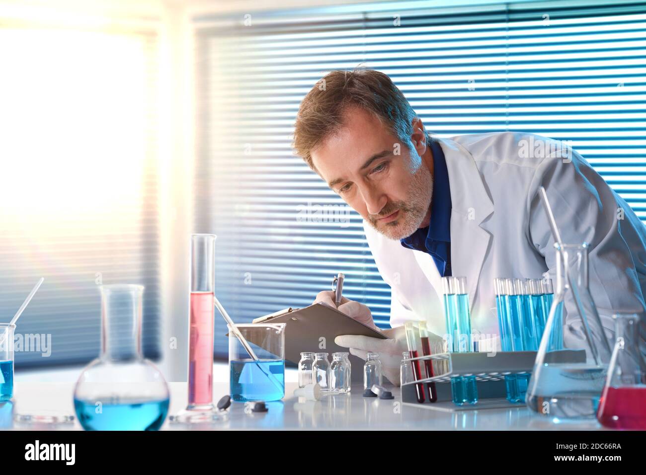 Scientist writing in a notebook supported on a laboratory with ...