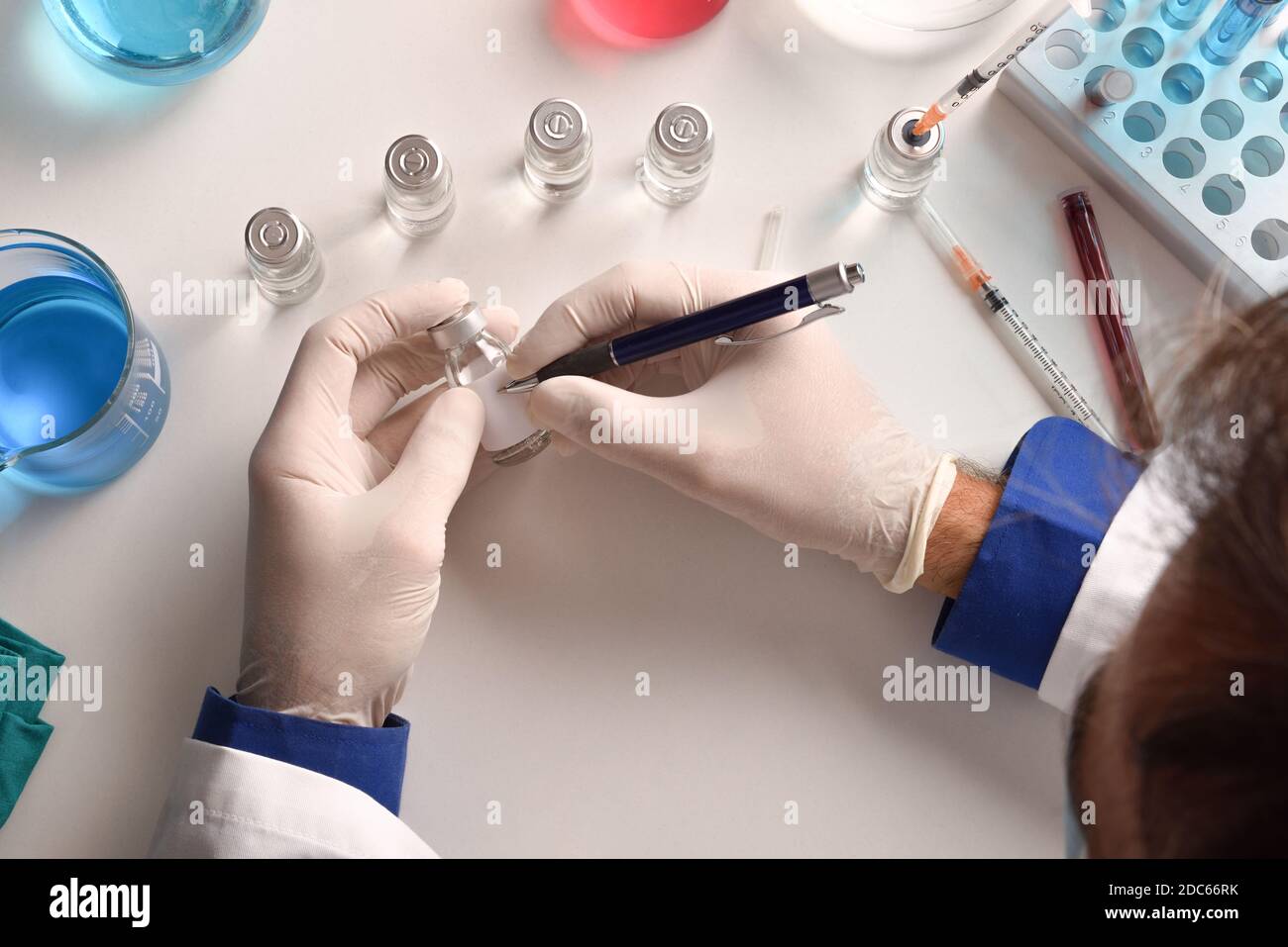 Medical worker writing on vial on laboratory table. Top view ...