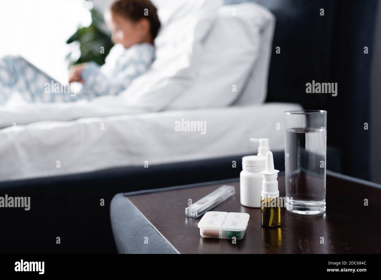 bedside table with glass of water and medicines near sick girl lying in ...