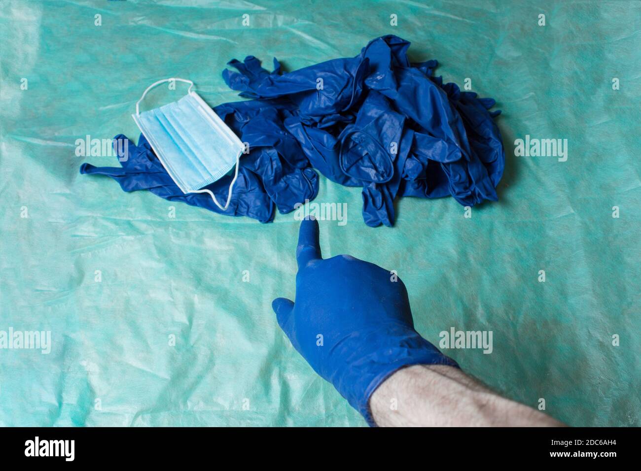 A blue gloved finger points to a pile of personal care equipment worn ...
