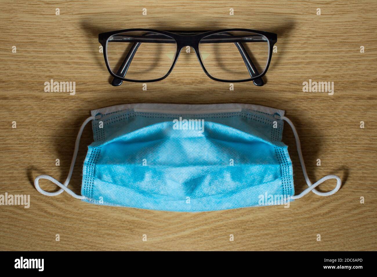 A glasses for work and a protective surgical mask on the wooden desk ...