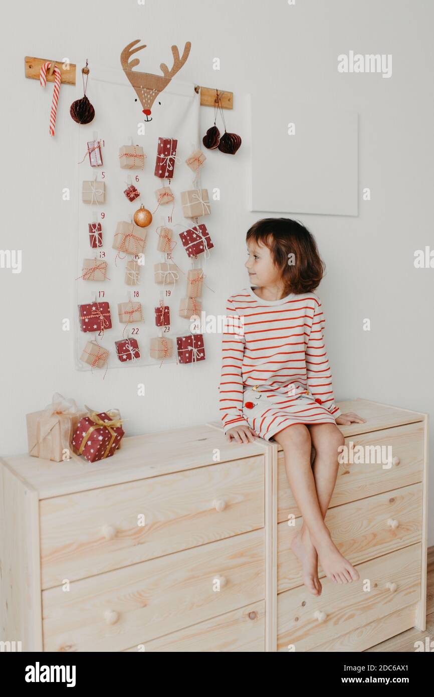 Cute girl opening Christmas Advent calendar gifts. Wrapped gifts for ...