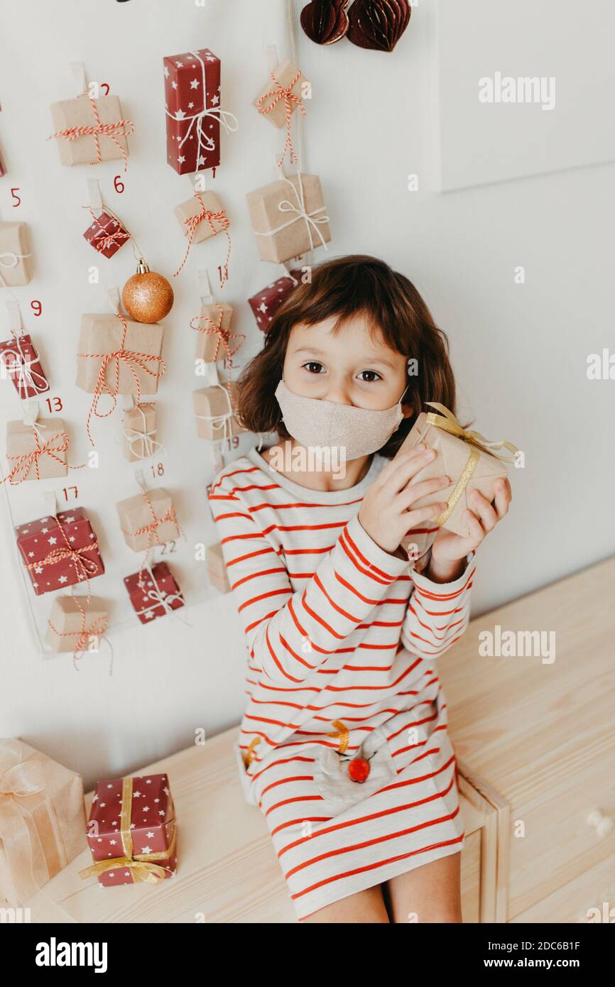 Cute girl wearing protective mask holding Christmas Advent calendar ...