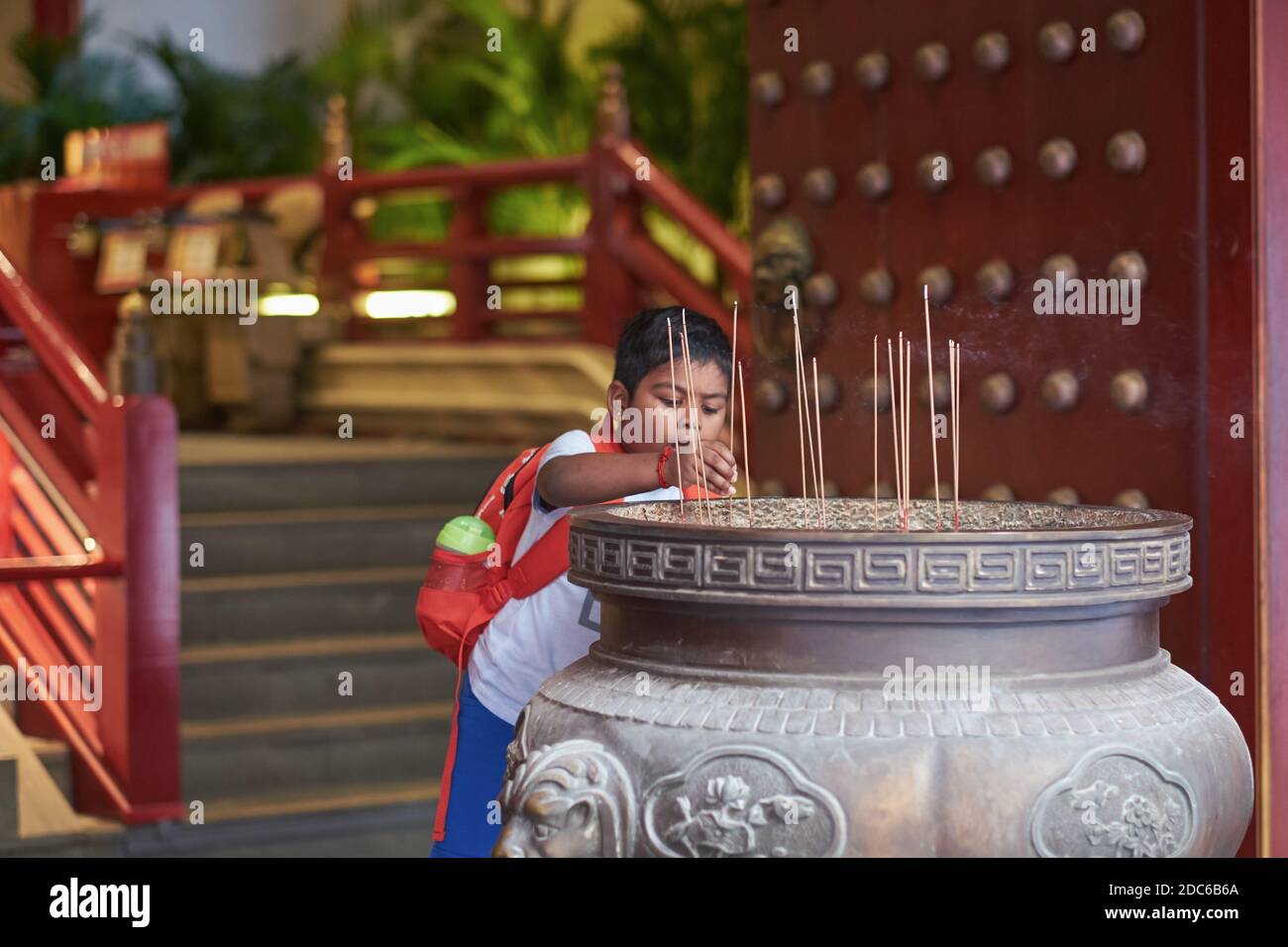 An ethnic Indian boy places joss sticks in a vessel at the (Chinese ...