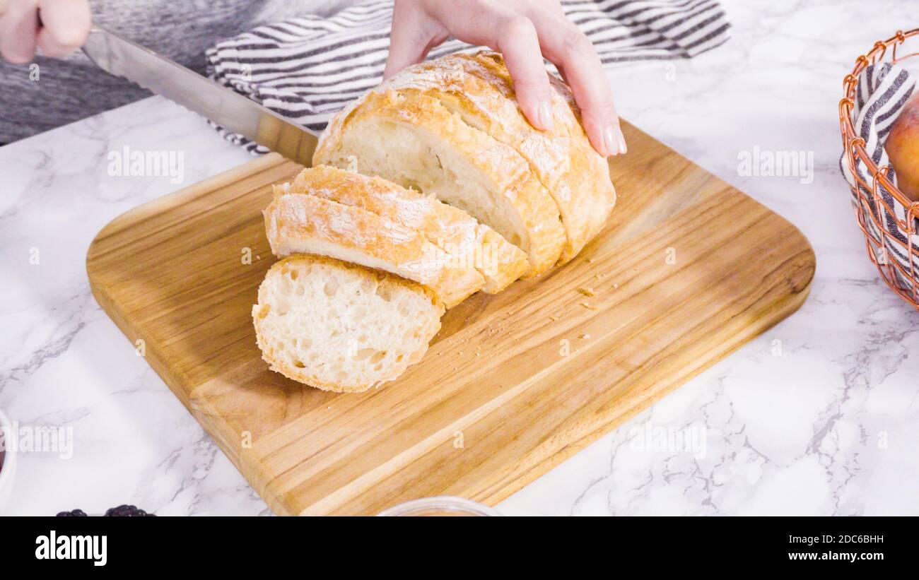Step by step. Slicing a loaf of ciabatta bread with a bread knife on a ...