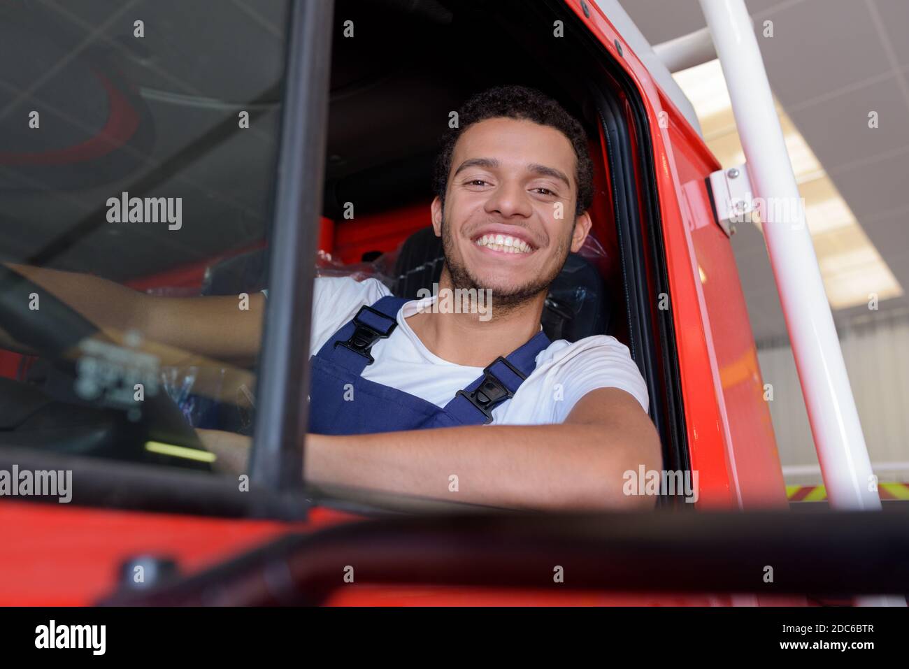 portrait of happy young fireman driving firetruck at station Stock ...