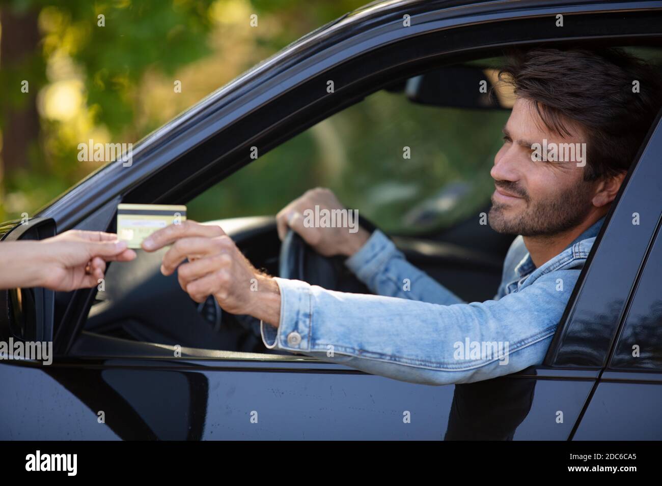 man paying with credit card while driving car Stock Photo - Alamy