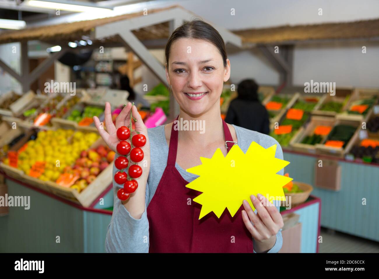 grocer holding cherry tomatoes and blank promotional sign Stock Photo ...