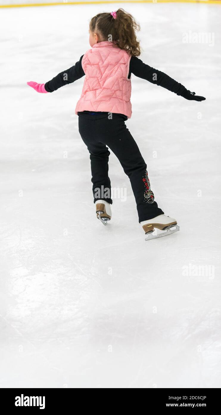 Little girl practicing figure skating elements on indoor ice skating ...