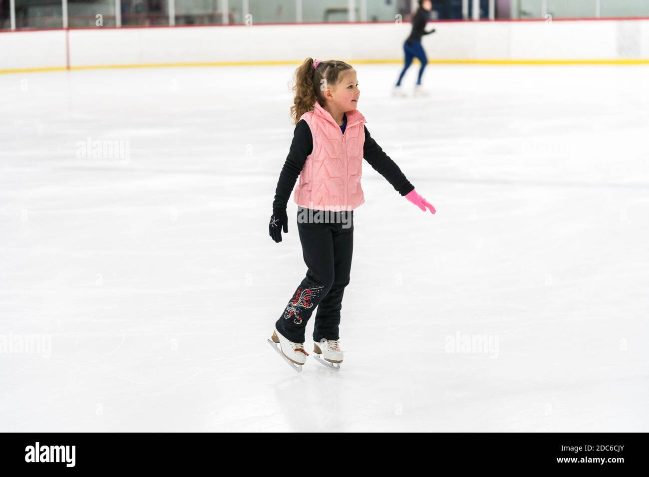 Little girl practicing figure skating elements on indoor ice skating ...