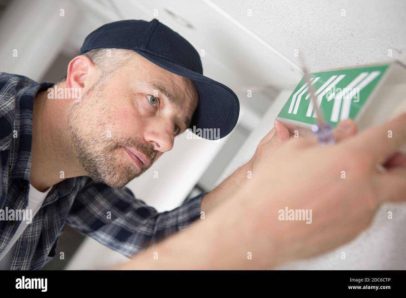 man fixing illuminated exit sign to wall Stock Photo - Alamy