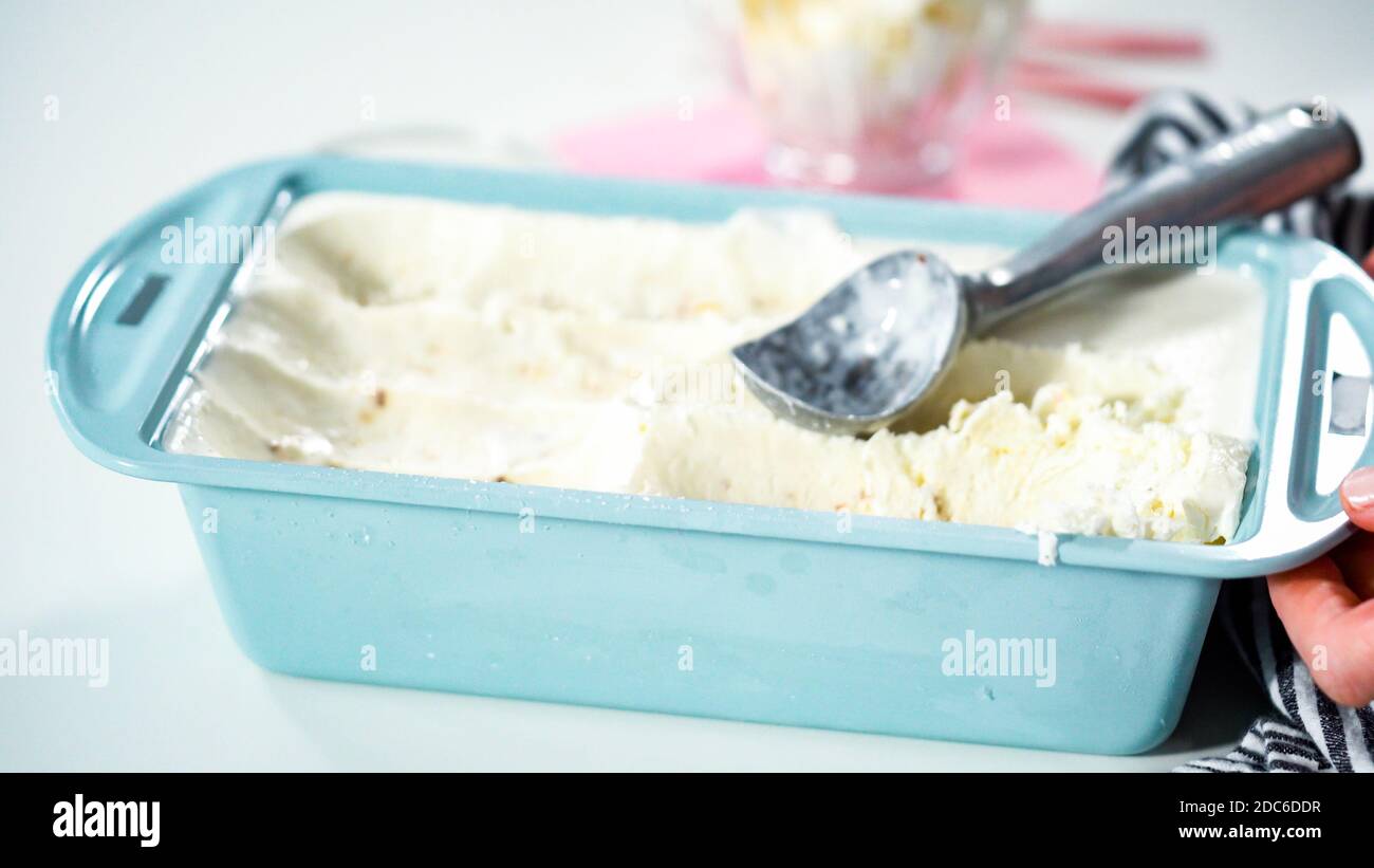 Scooping homemade coconut ice cream into a glass ice cream bowl Stock ...