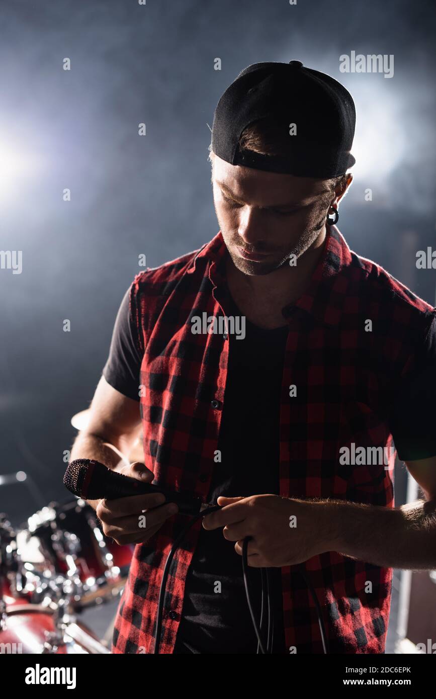 Rock band vocalist holding microphone and touching wire on blurred ...