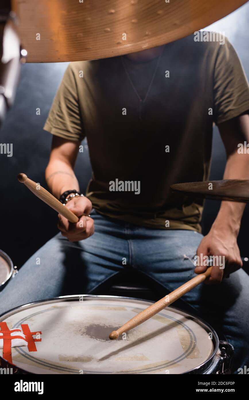 Obscure face of musician with drumsticks playing drum on black Stock ...
