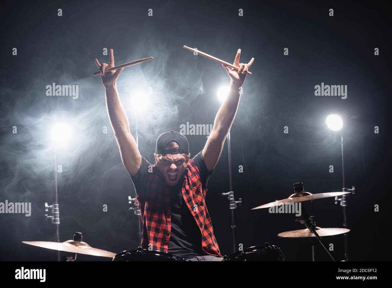 Angry drummer showing rock signs yelling, while sitting at drum kit ...