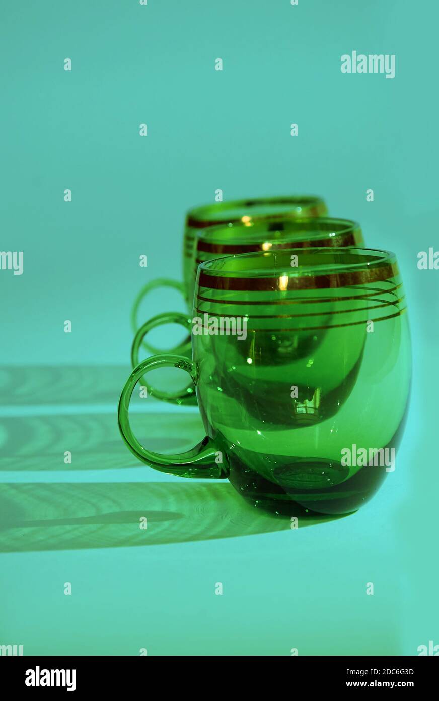 three green glass cups with handles stand in a row on a blue background ...