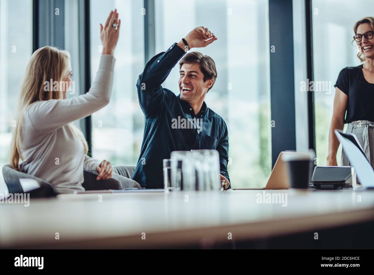 businessman giving a high five to his coworker while their female ...