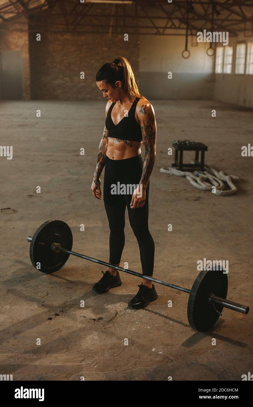 fitness woman with barbells on floor at old factory shade. Female ...