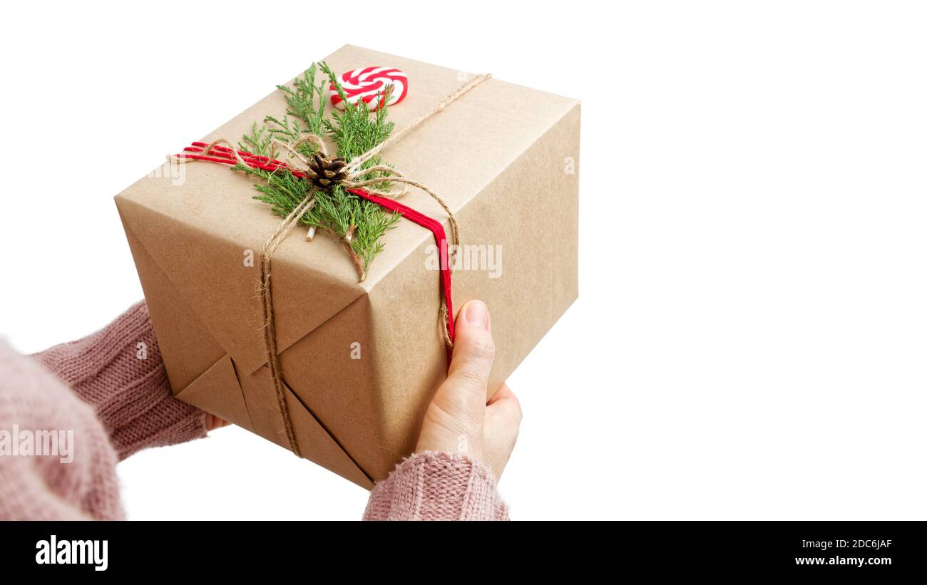 Female hands holding gift box wrapped in kraft paper and tied with ...