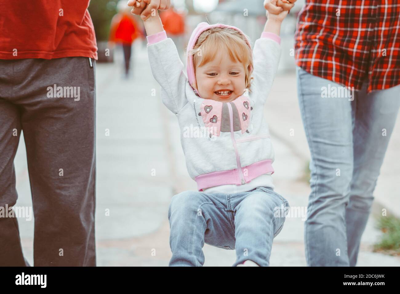 parents walk with child holding hands child laughs Stock Photo - Alamy