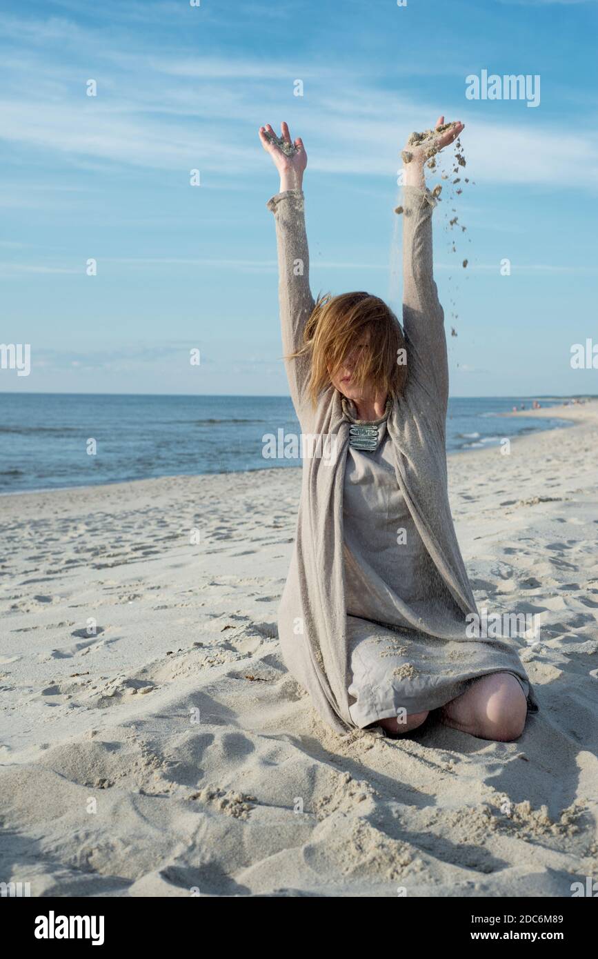Woman pouring sand on her head on the beach Stock Photo - Alamy