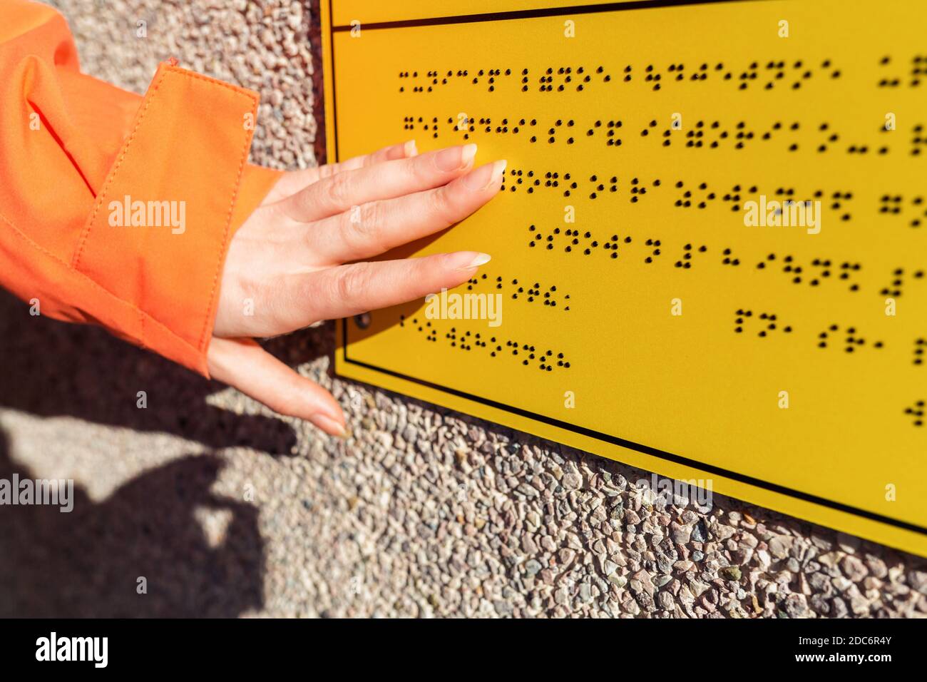 A woman's hand reads a yellow Braille sign. Close up. Concept of the ...