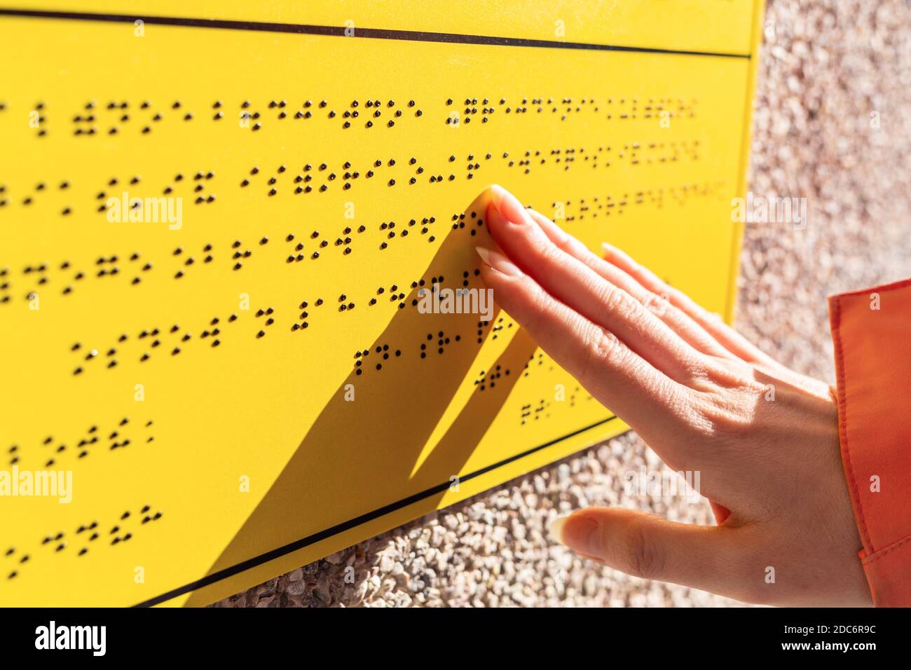 Blindness. A woman reads a yellow Braille sign. Close up of hands ...