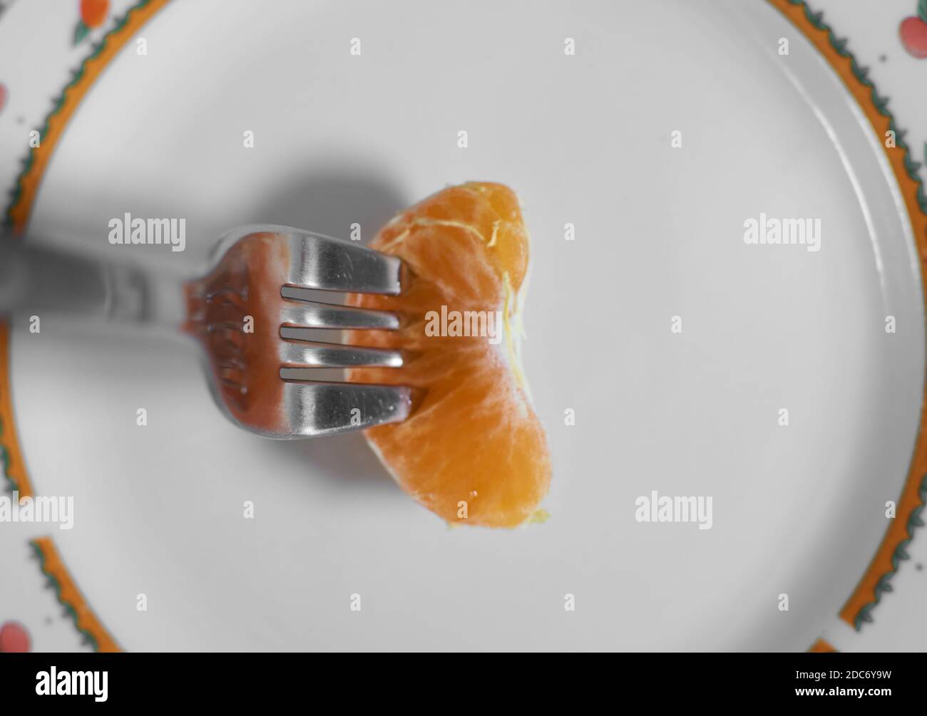 A high angle shot of a tangerine and a fork on a plate Stock Photo - Alamy