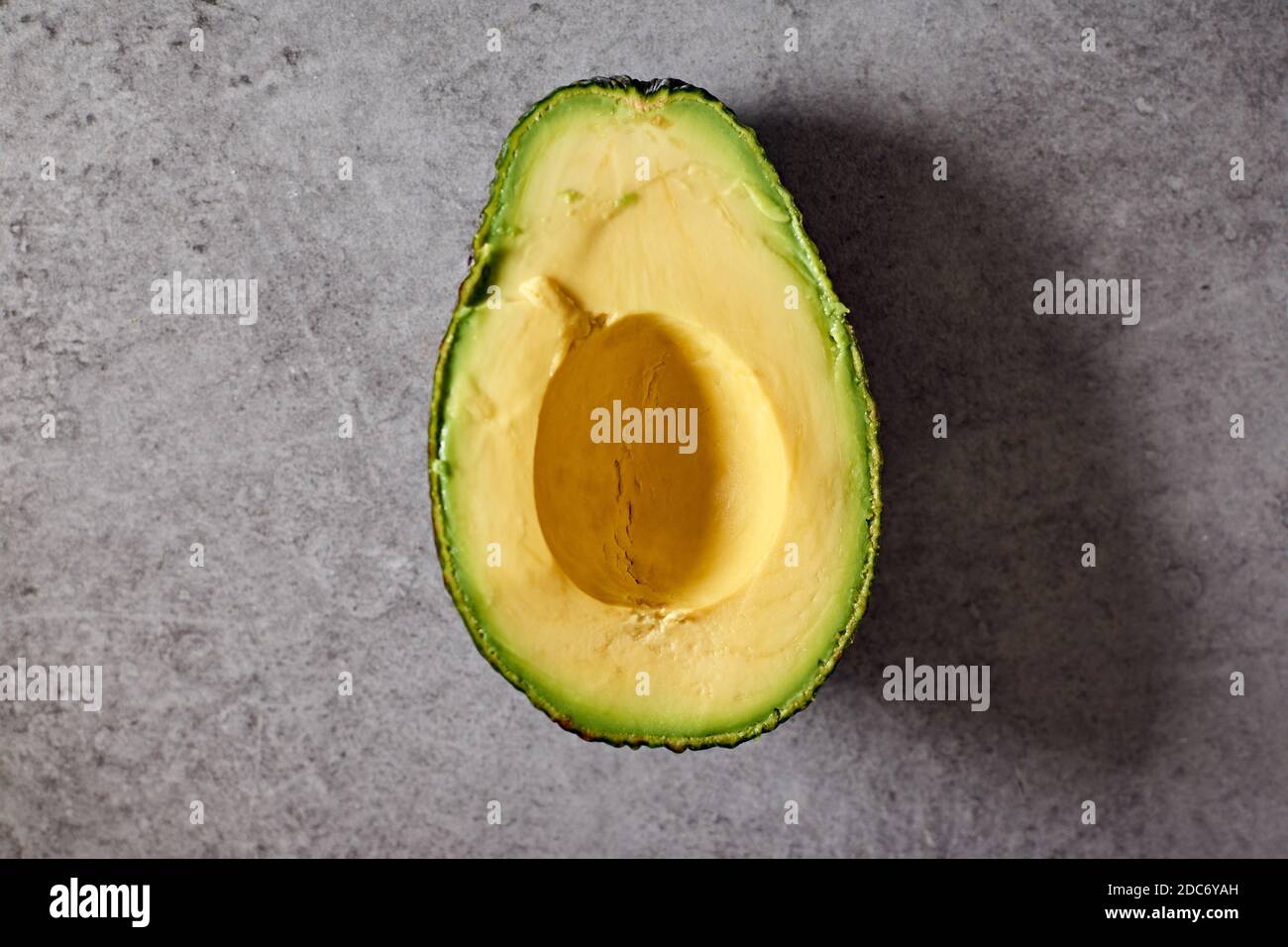 A high angle shot of a half of an avocado on a rough surface Stock ...